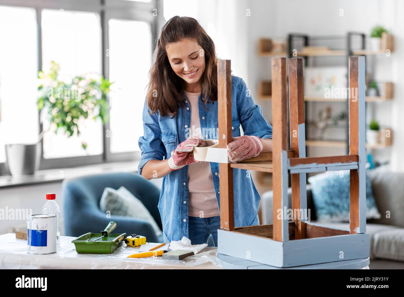 woman sticking masking tape to table for repaint Stock Photo - Alamy