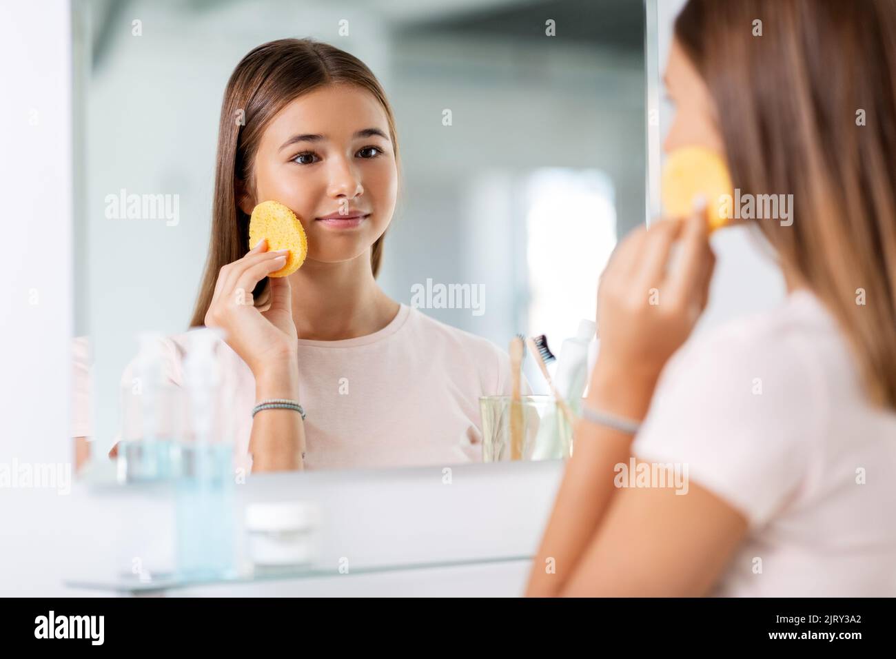 teenage girl cleaning face with sponge at bathroom Stock Photo - Alamy