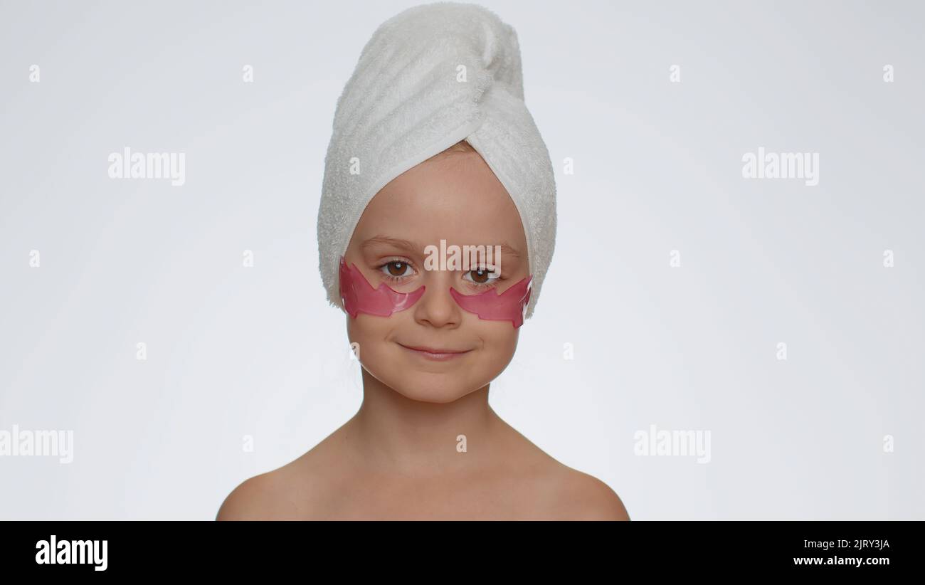 Beautiful young smiling child girl in towel on head applying pink ...