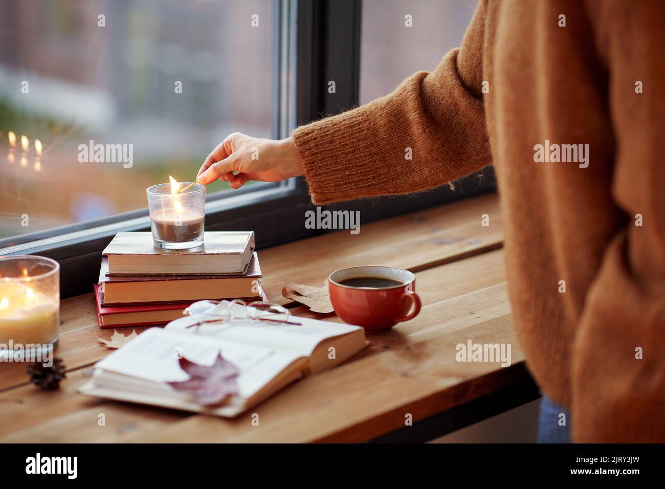 hand with match lighting candle on window sill Stock Photo - Alamy