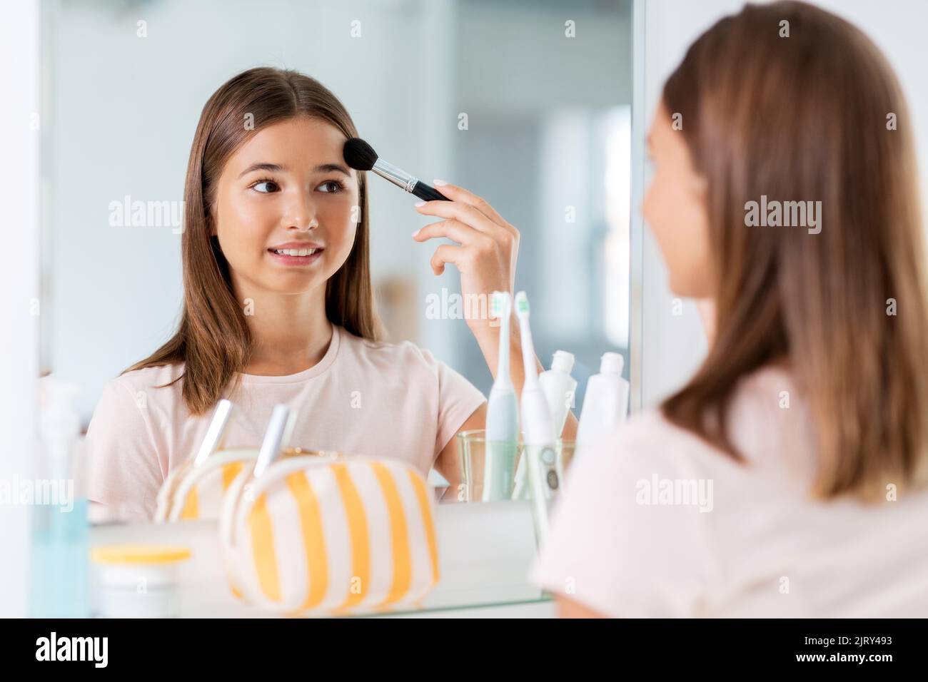 teenage girl applying powder to face at bathroom Stock Photo - Alamy