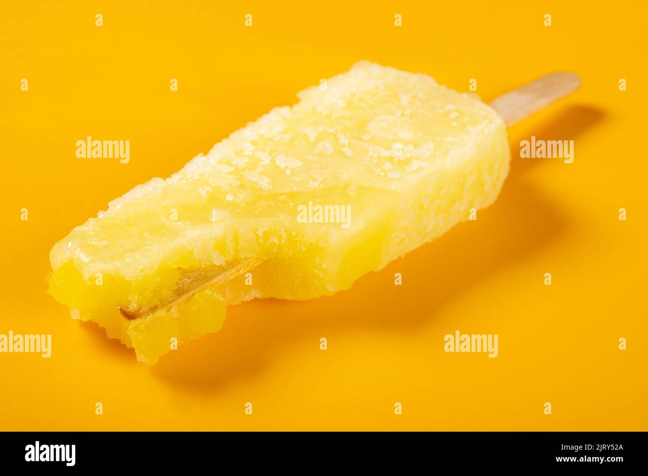 angle view orange color popsicle with some bites on an orange color ...