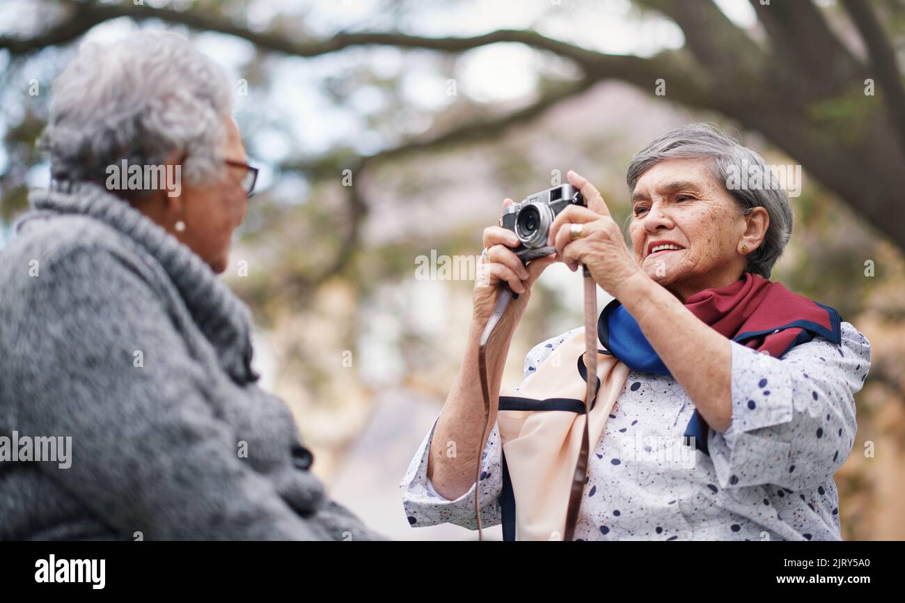 Happy old woman taking photo of friend using camera in park Stock Photo ...