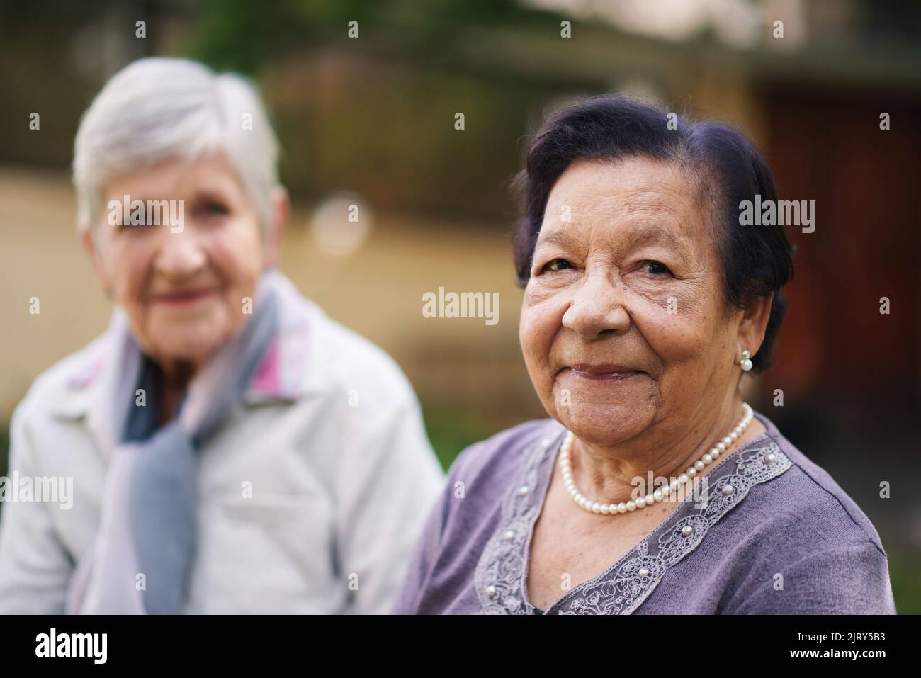 Two elderly women sitting on bench in park smiling happy life long ...