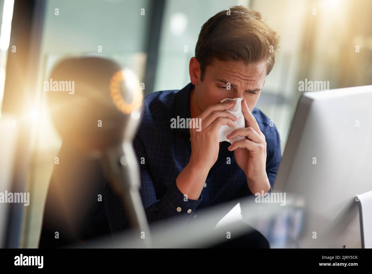 I just need a time-out from work. a young businessman blowing his nose ...