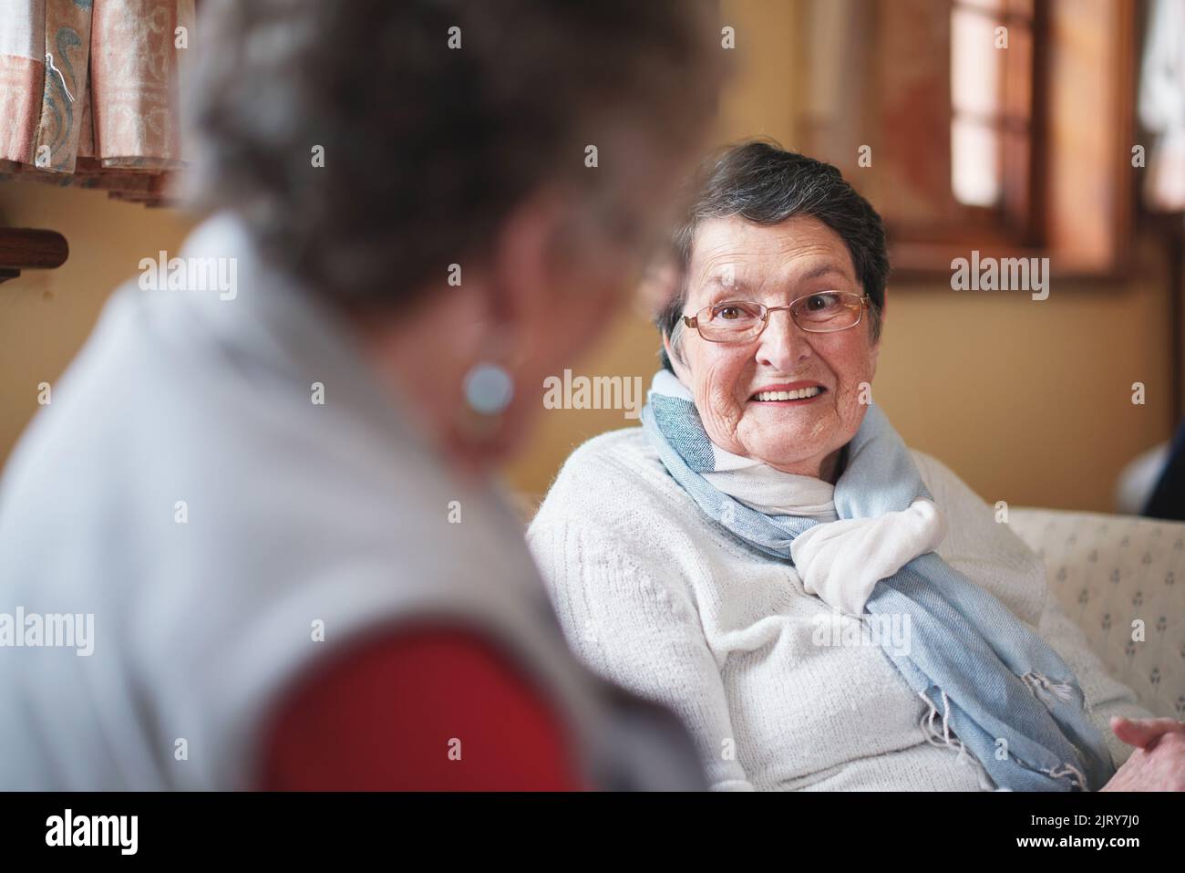 Happy elderly woman talking to friend sitting on sofa in retirement ...