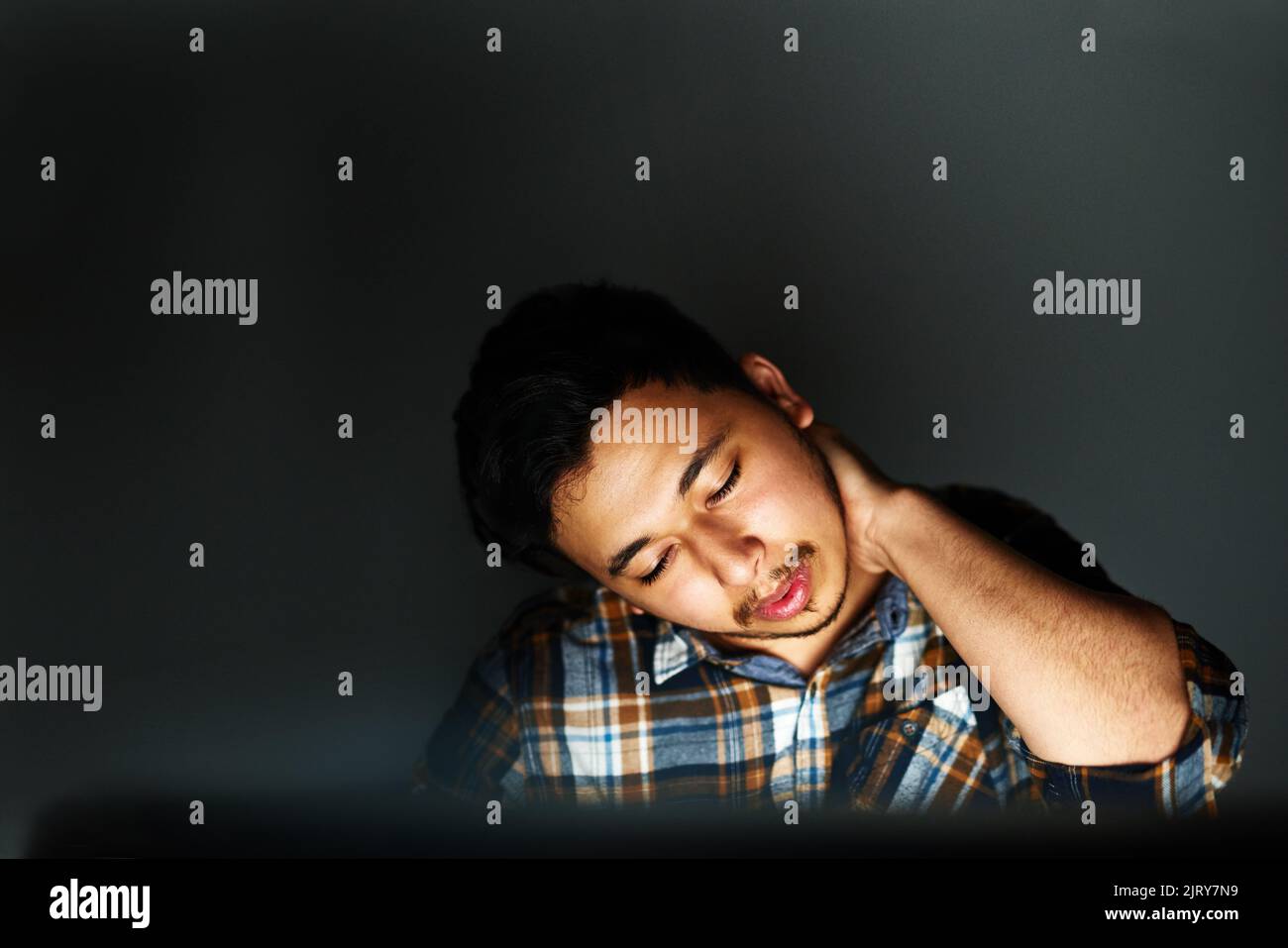 Long hours are taking their toll. a young designer massaging his sore ...