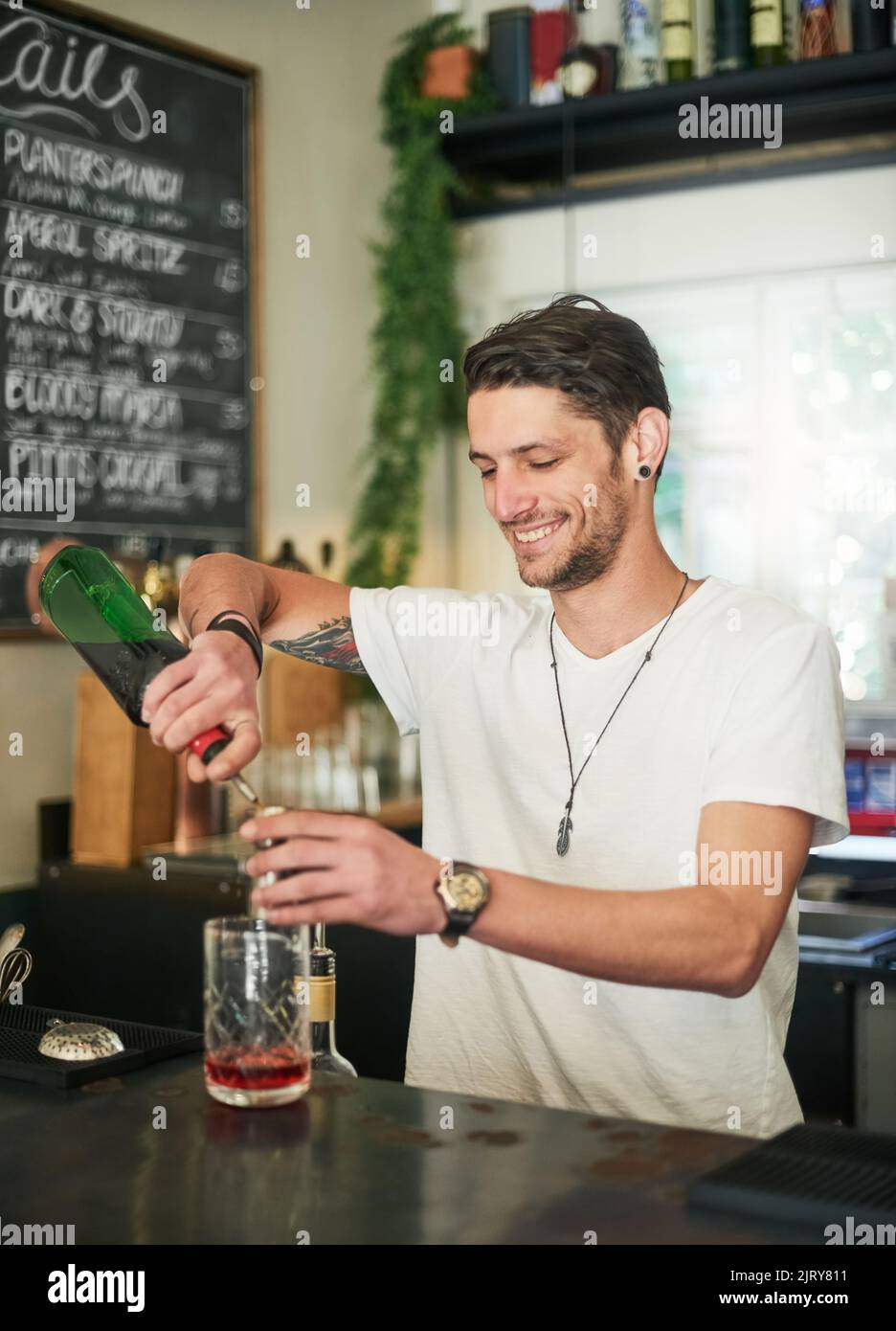 Making it look easy. a happy young bartender mixing a cocktail while ...