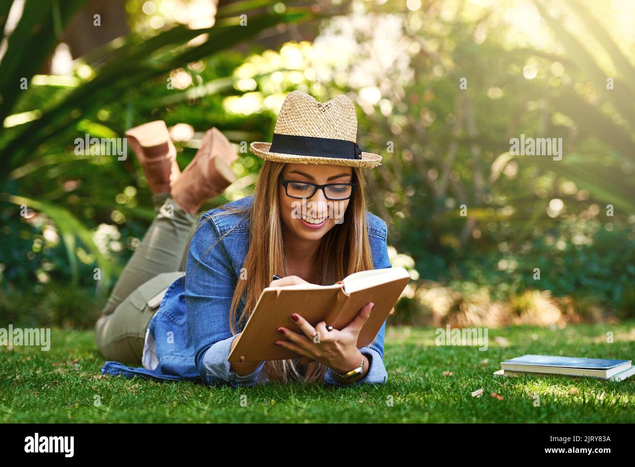 Outside with her favourite book. an attractive young woman reading a ...