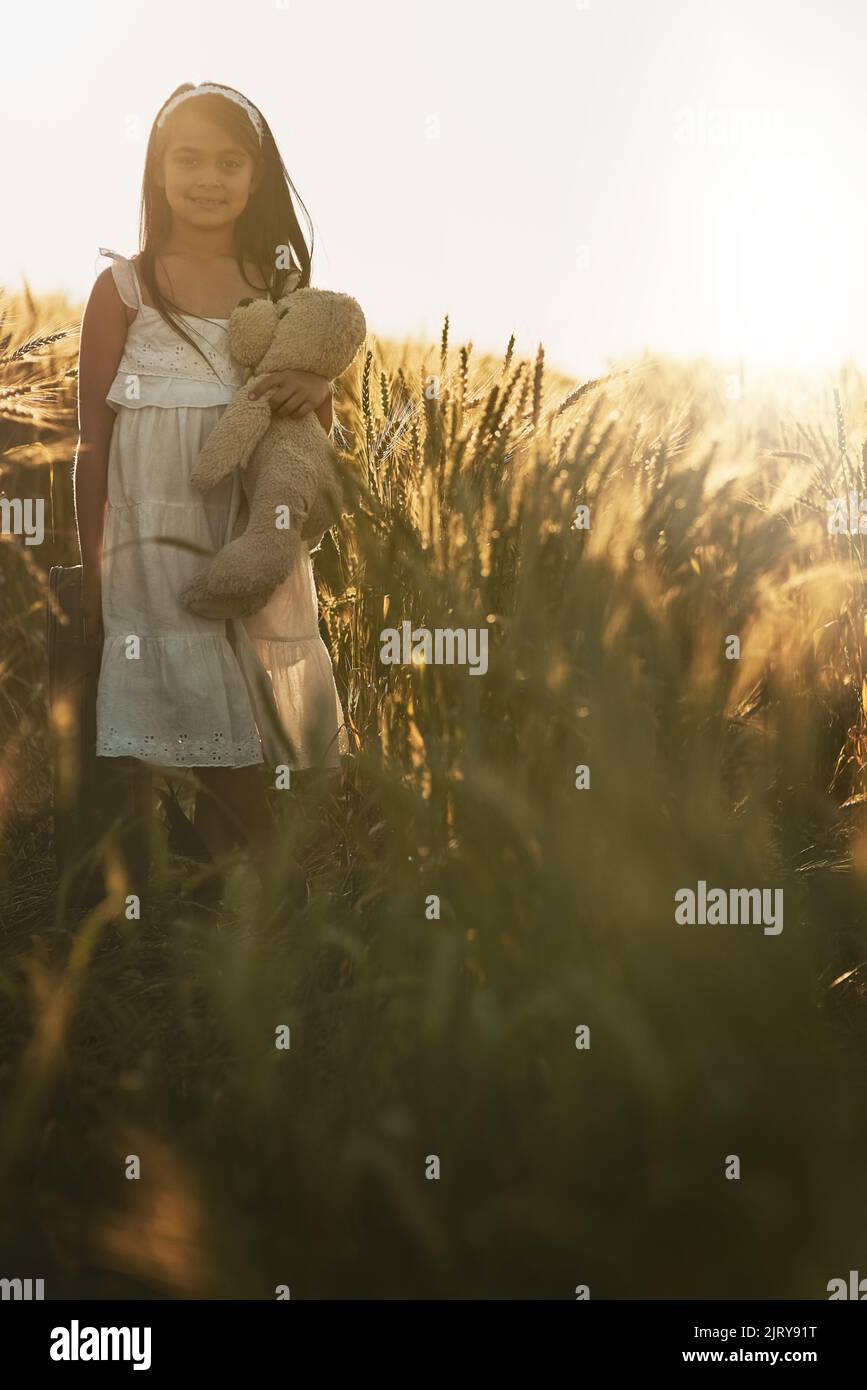 Enjoying a fun day on the farm. Portrait of a cute little girl playing with her teddybear in a ...