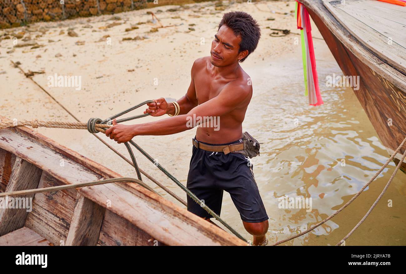 Preparing to take to the ocean. a Thai man preparing his boat before ... Preparing to take to the ocean. a Thai man preparing his boat before ...