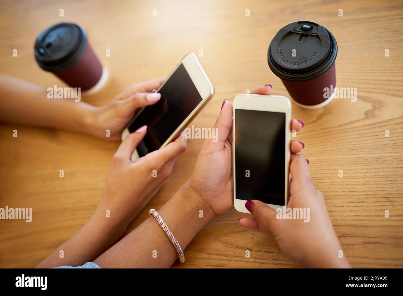 Cafe connections. two young woman using their cellphones in a cafe ...