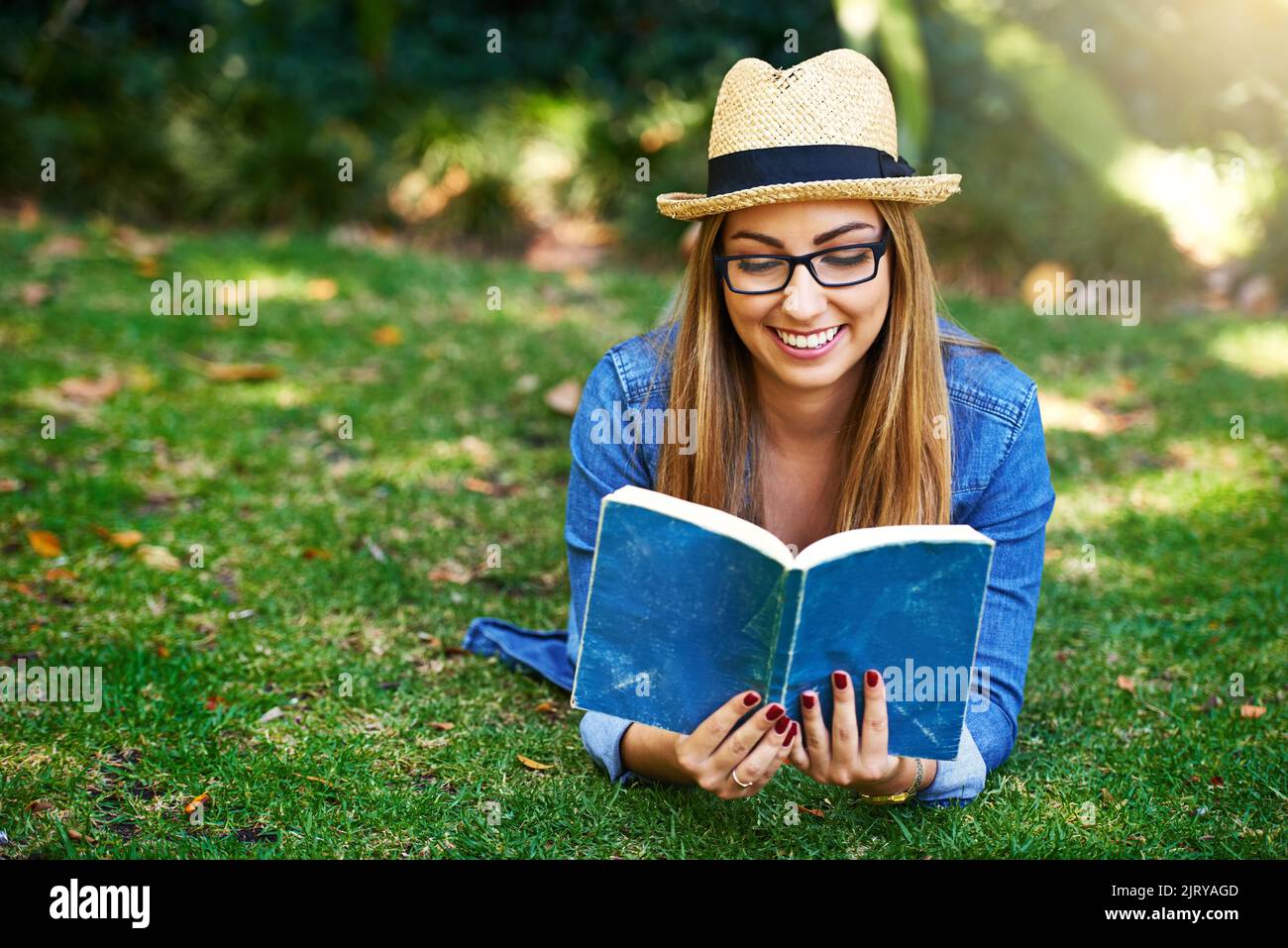 She loves to read. an attractive young woman reading a book while lying ...