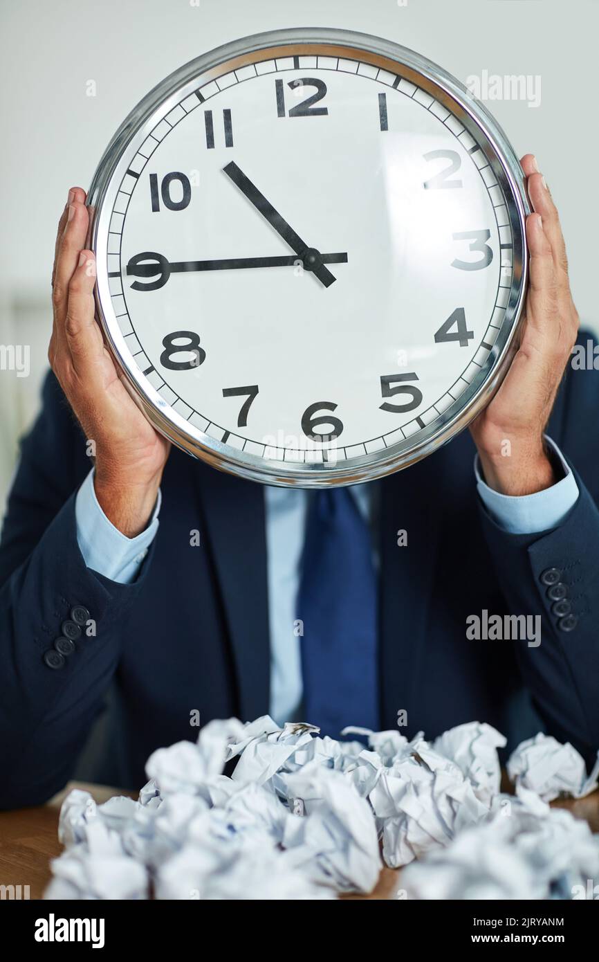 Running out of time. an unrecognizable businessman holding a large ...