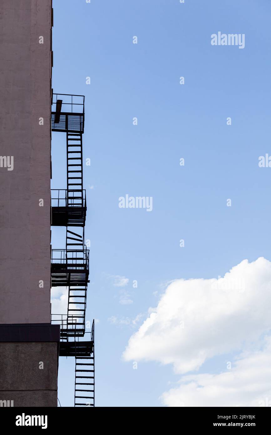Silhouette of a fire escape on a high-rise building against a blue sky ...