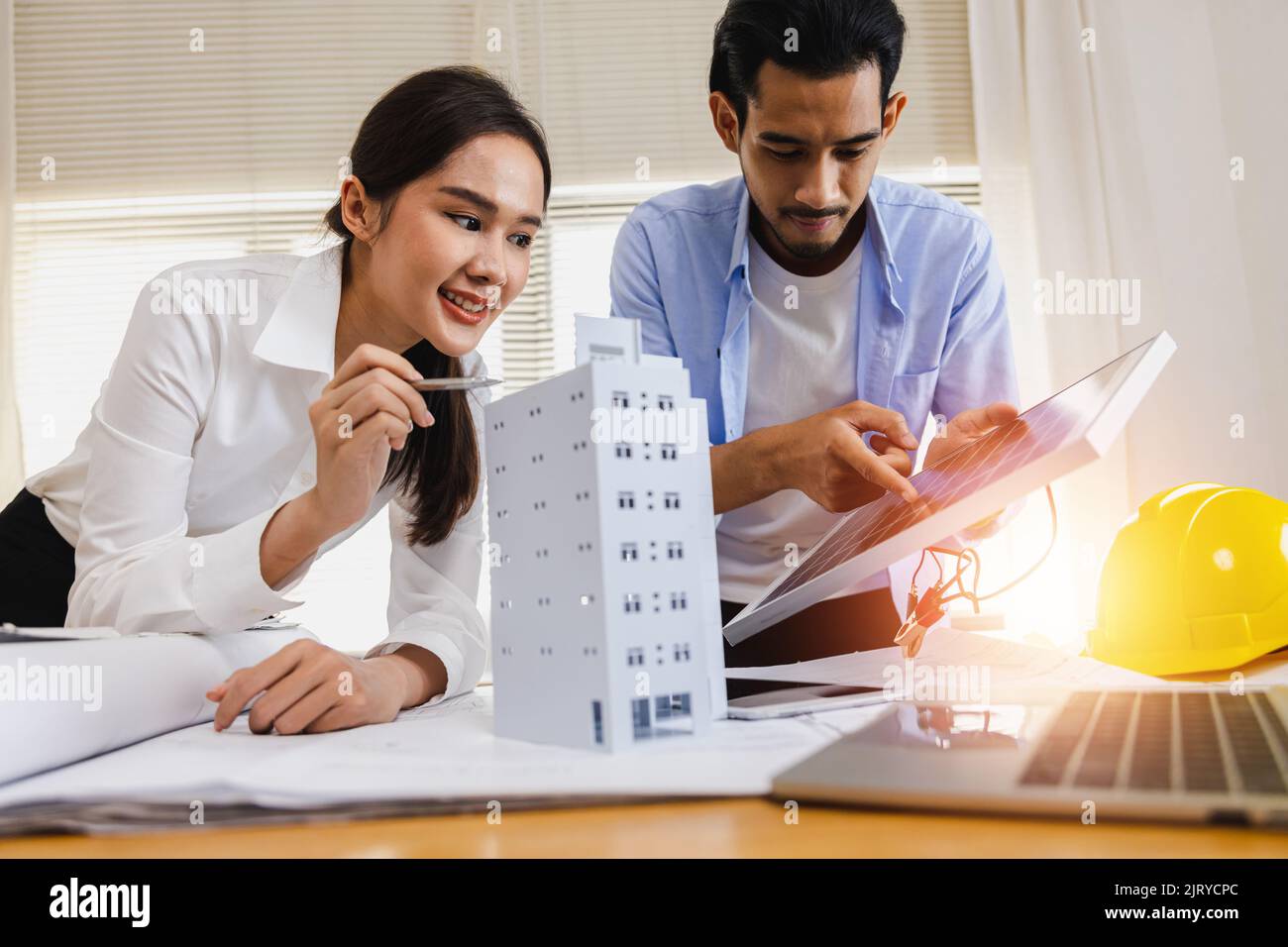 Asian engineer woman point on building model and man check on solar ...