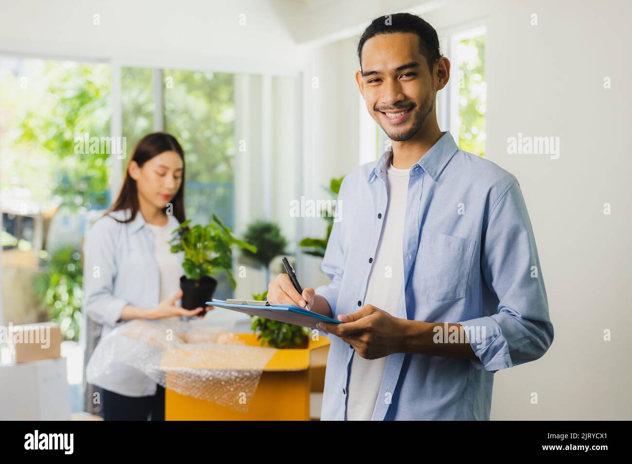 Portrait of Asian delivery man, courier checking packing box before ...