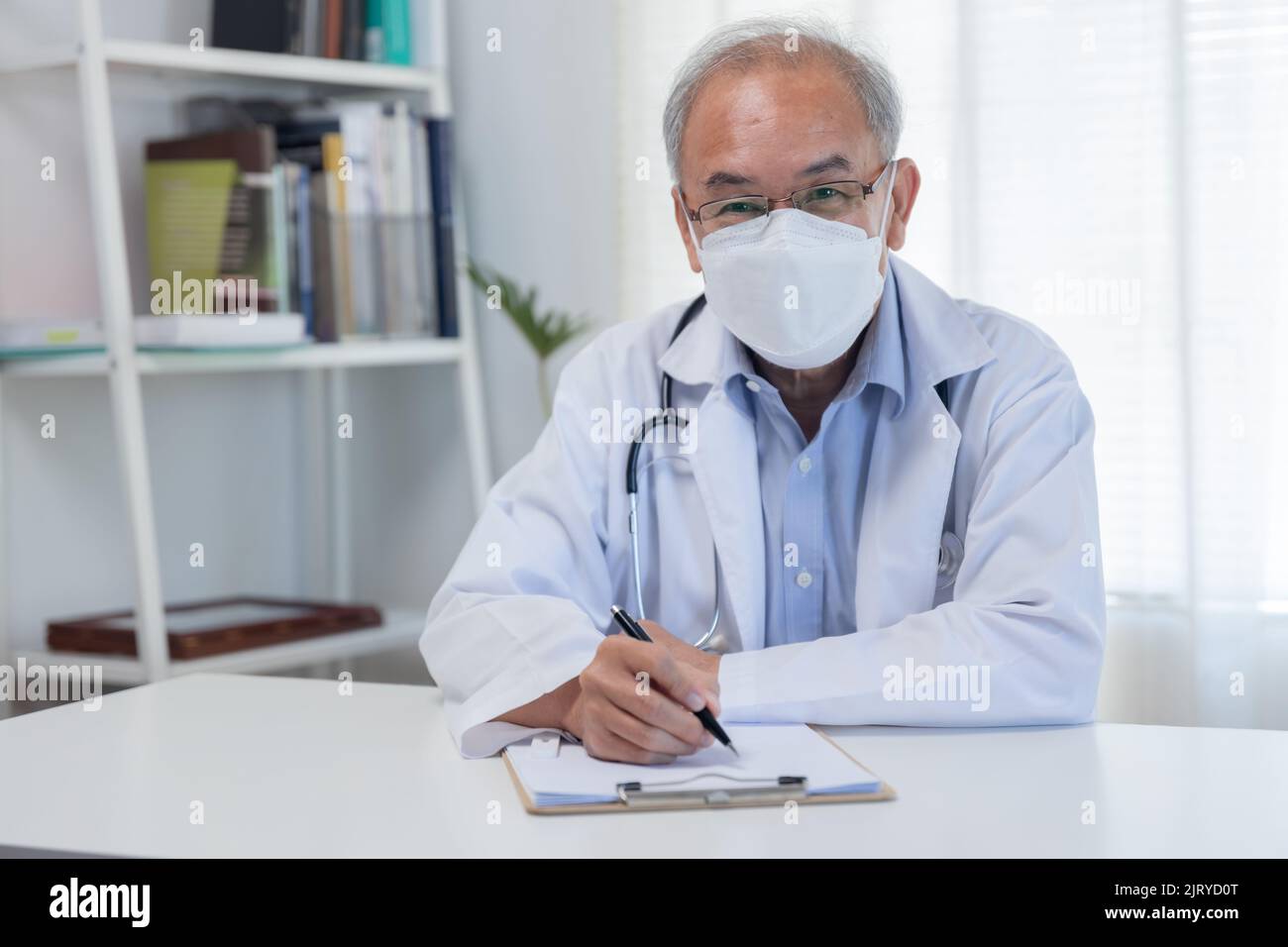 Portrait old man doctor sit in clinic and wearing face mask Stock Photo ...