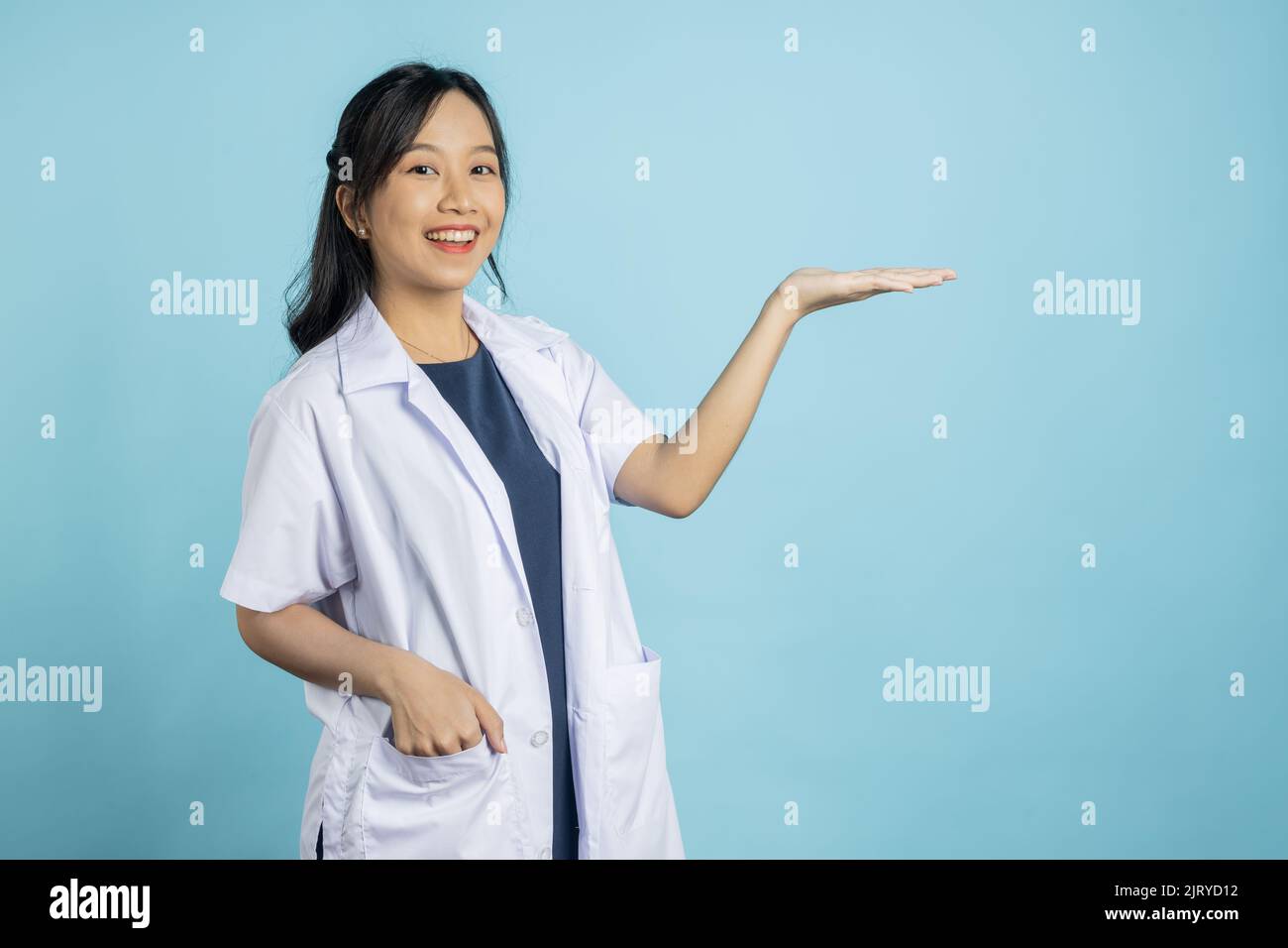 Portrait beautiful Asian doctor smiled, show and present on blue ...