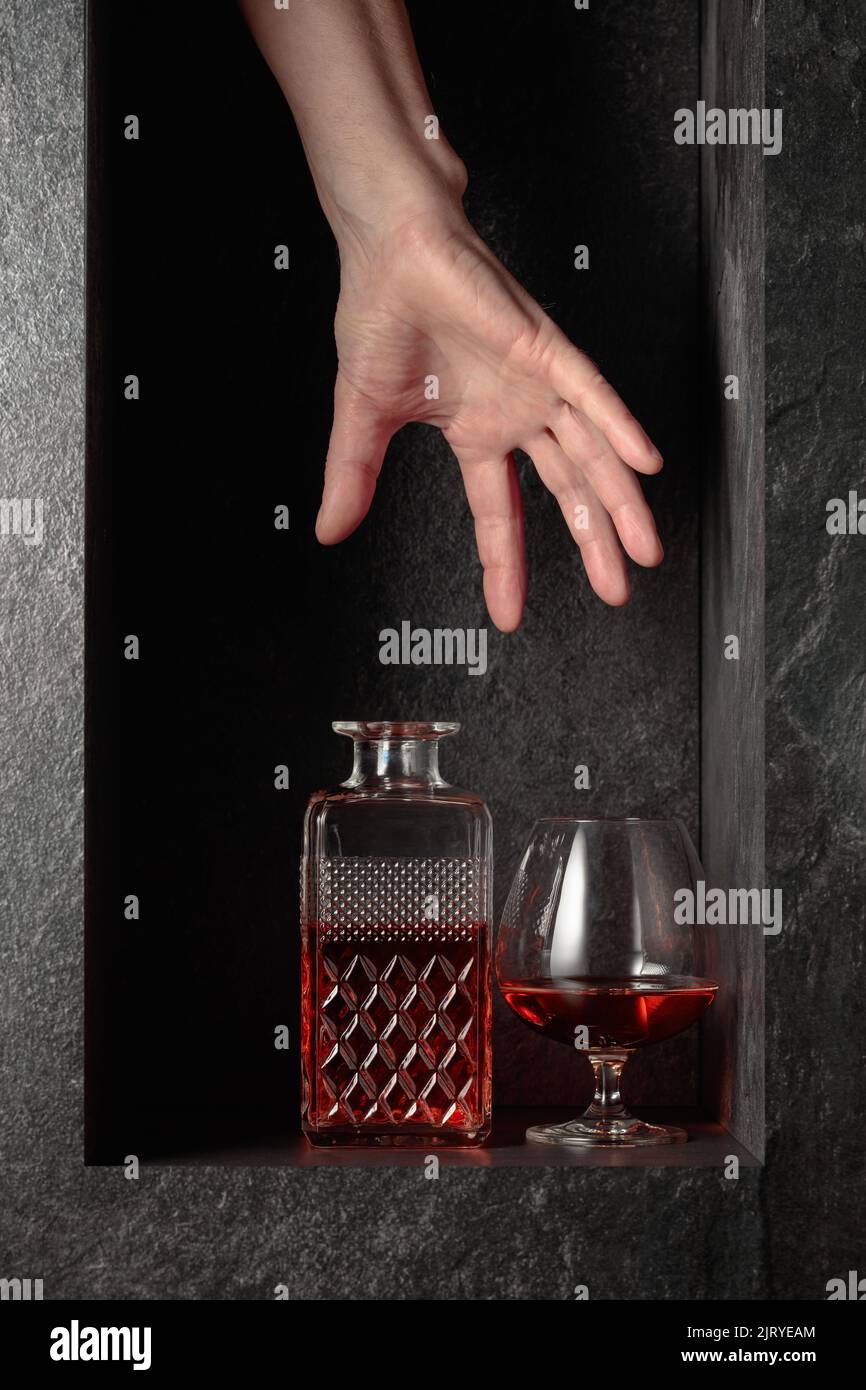 Hand reach for a decanter of brandy. A concept image on the theme of ...