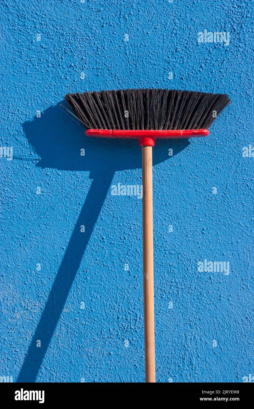 Red broom leaning against a blue house wall, Italy Stock Photo - Alamy