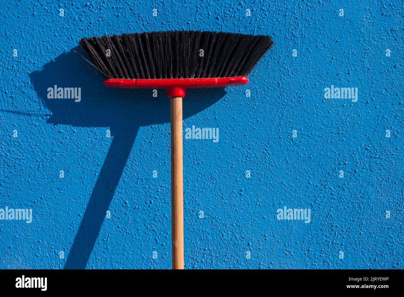 Red broom leaning against a blue house wall, Italy Stock Photo - Alamy