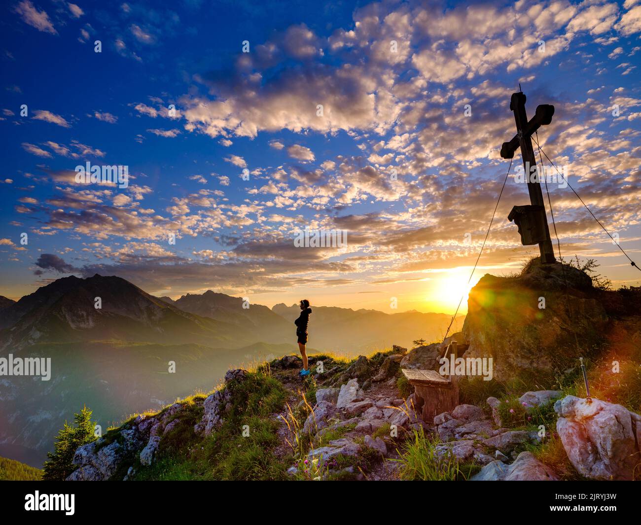 Mountaineer standing at sunset at the summit cross of the Brettgabel ...