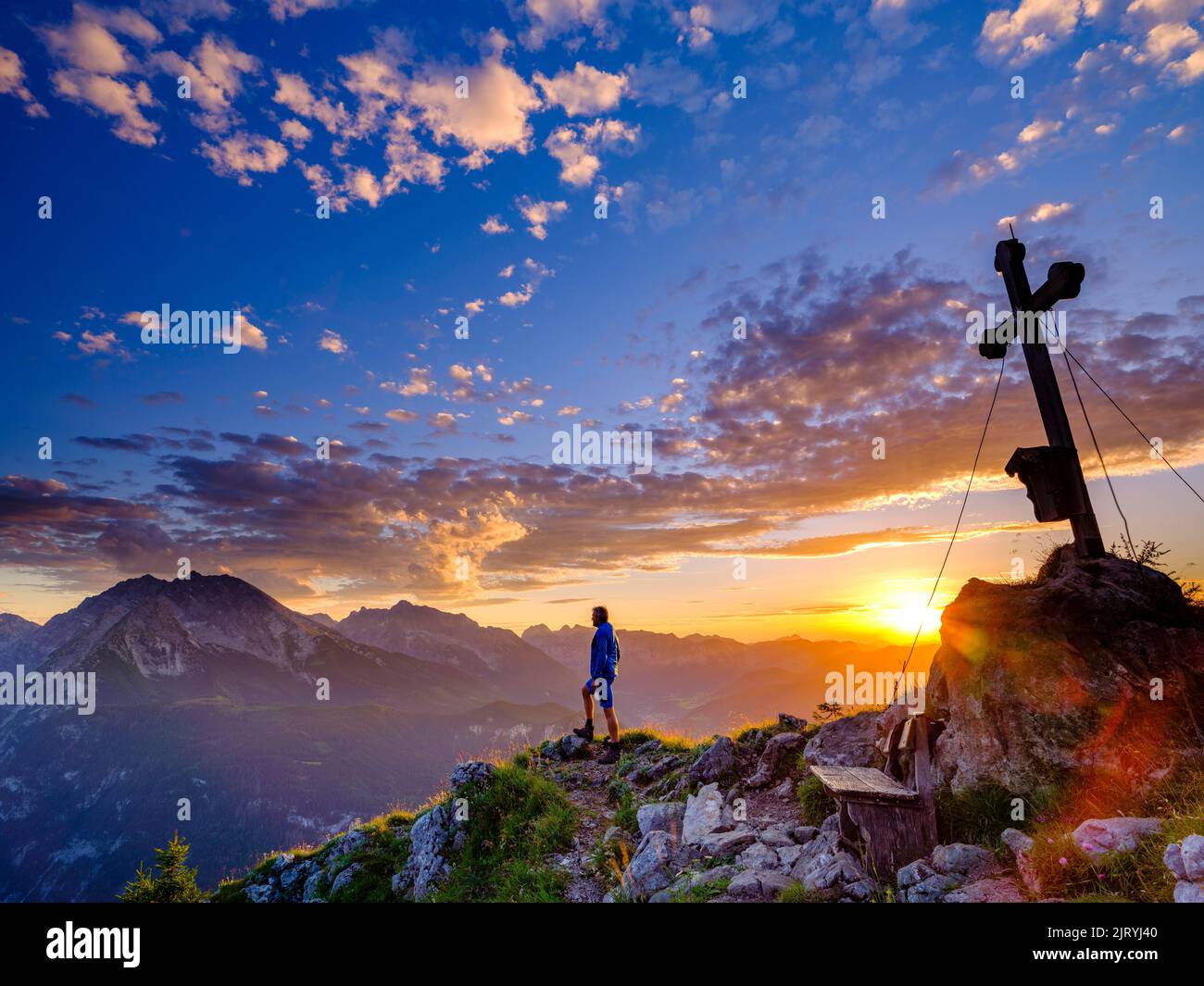Mountaineer standing at sunset at the summit cross of the Brettgabel ...