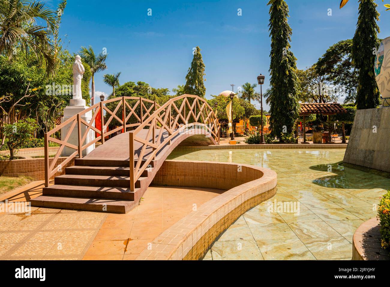 View of a calm park with a small wooden bridge over a water fountain ...