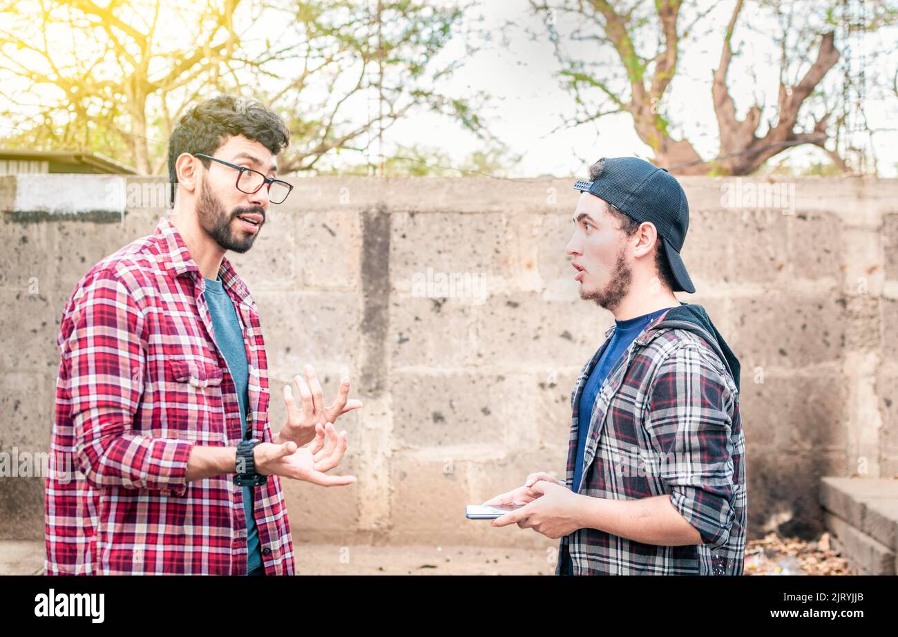 Two young friends talking face to face positively on the street. Side ...