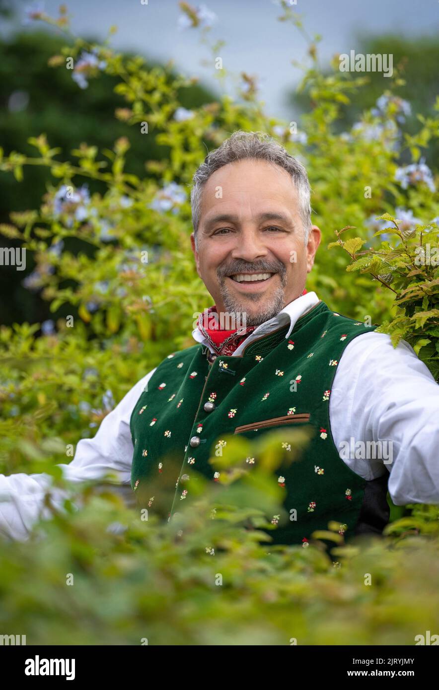 Laughing middle-aged man in Bavarian traditional costume standing by a ...
