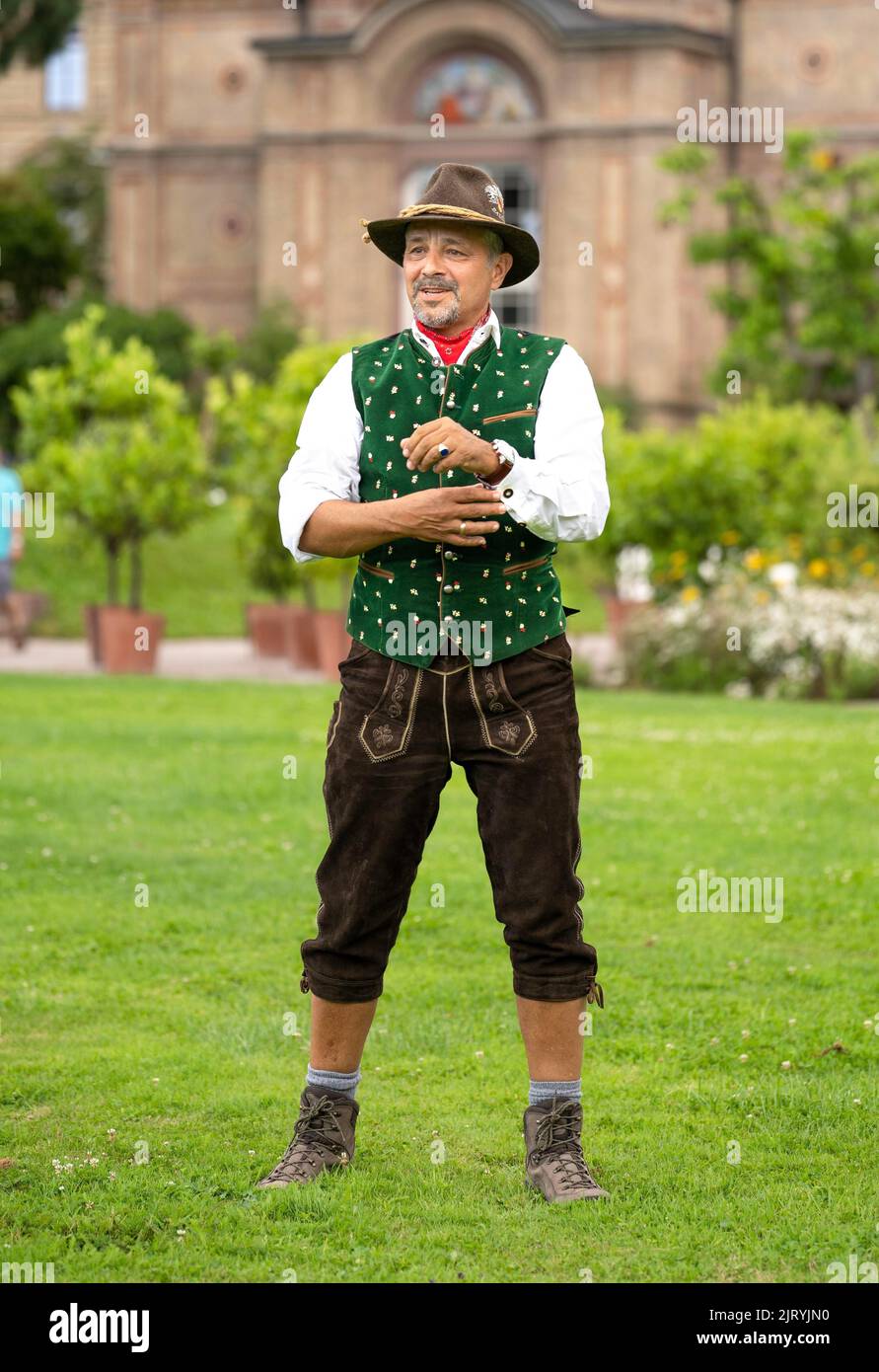 Man in Bavarian traditional costume with hat standing on green lawn ...