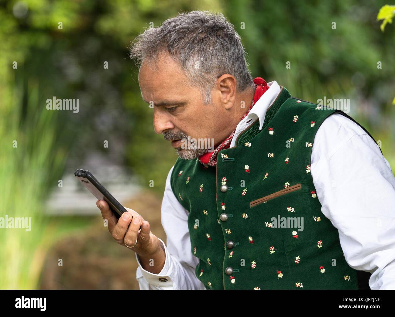 Middle-aged man in Bavarian traditional costume looking confused at his ...