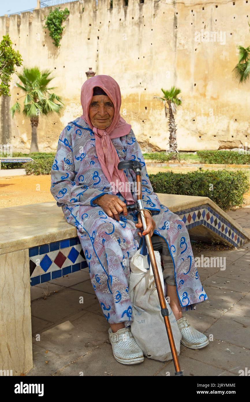 Old woman in traditional djellaba or kauezen coat, city wall in the ...