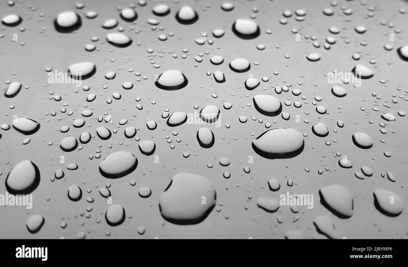 Rain drops beading on a smooth glass surface, low angle view with ...