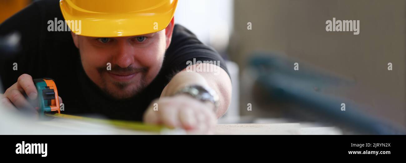 Man builder in helmet makes measurements with tape measure. Handmade ...