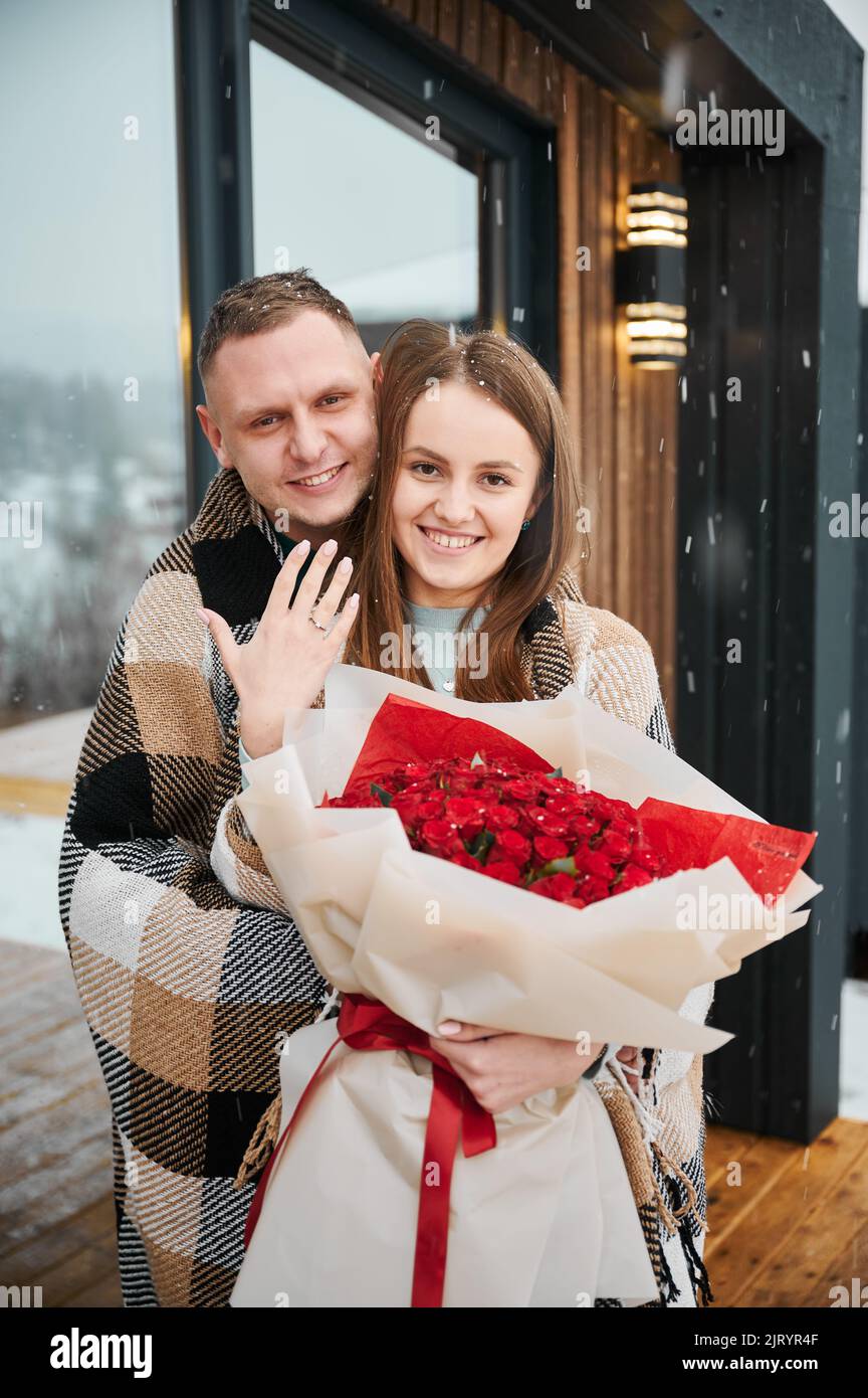 Happy woman holding bouquet of roses and showing hand with engagement ...