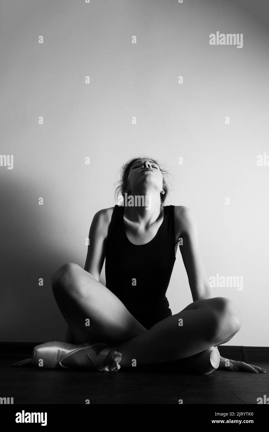 tired ballerina sitting on floor, resting with closed eyes, monochrome ...