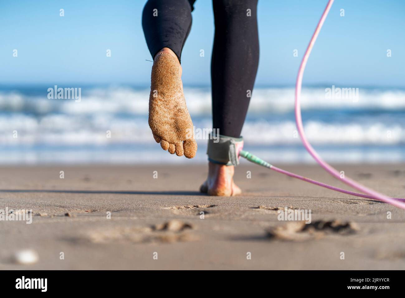 Surfer walking at the beach colse up with her surfboard in the morning ...