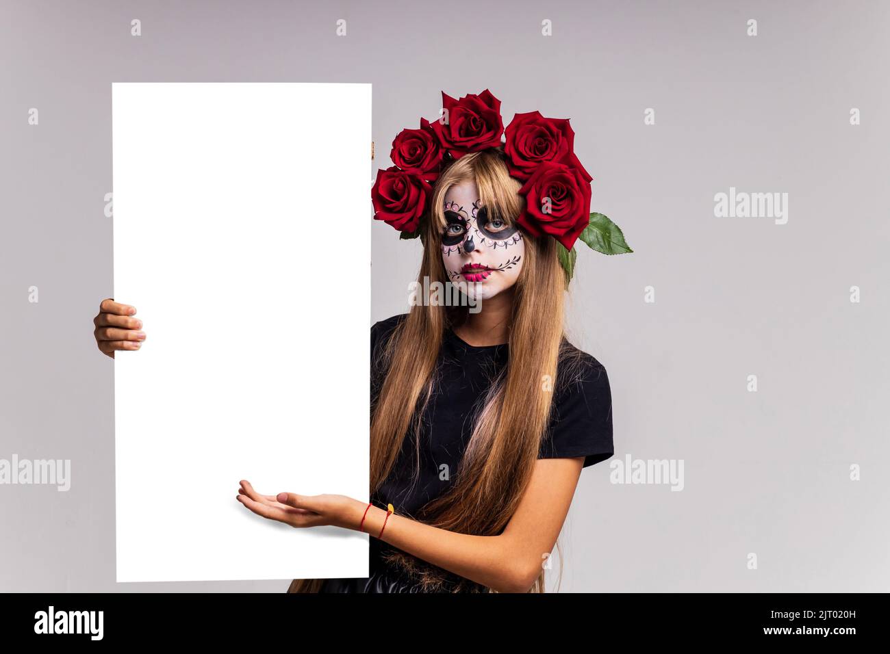 teenager girl with cool skull makeup with roses on head looking at ...