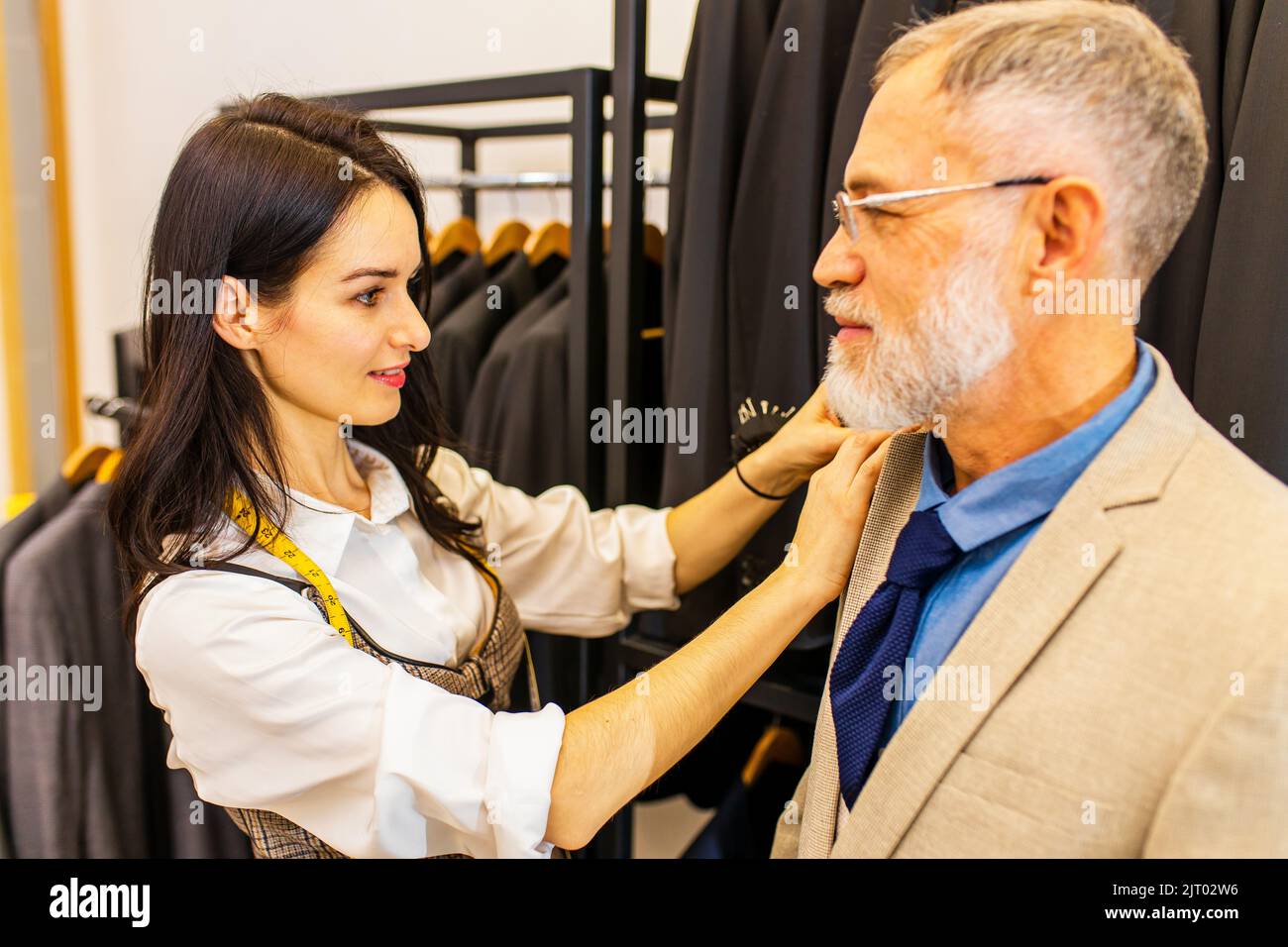 a professional tailor woman trying on a tailor-made suit for an elderly man Stock Photo - Alamy