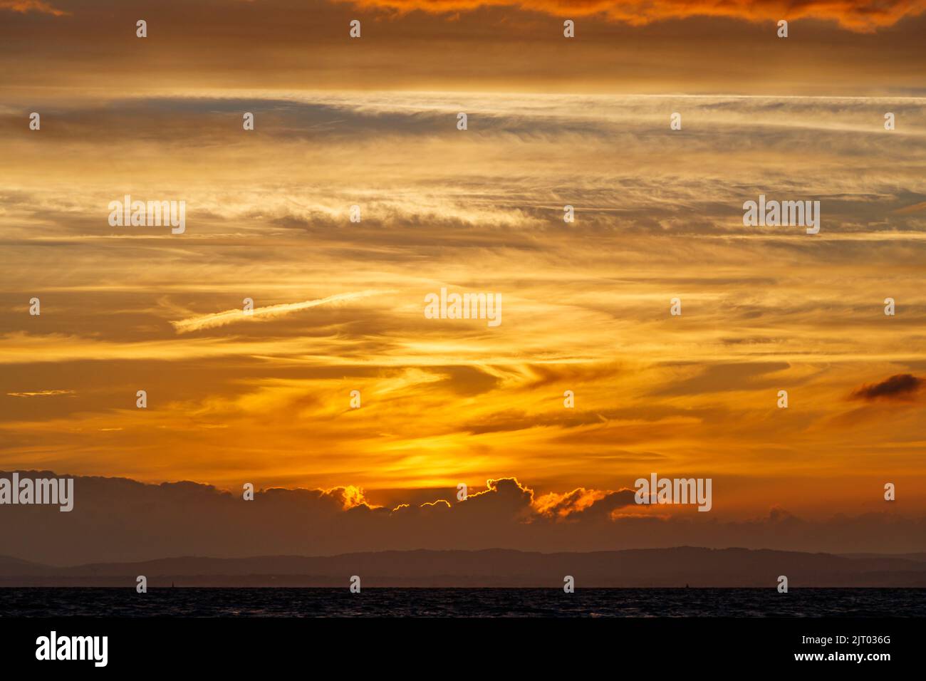 Golden glow with the setting sun lighting up the cloud cover Stock ...