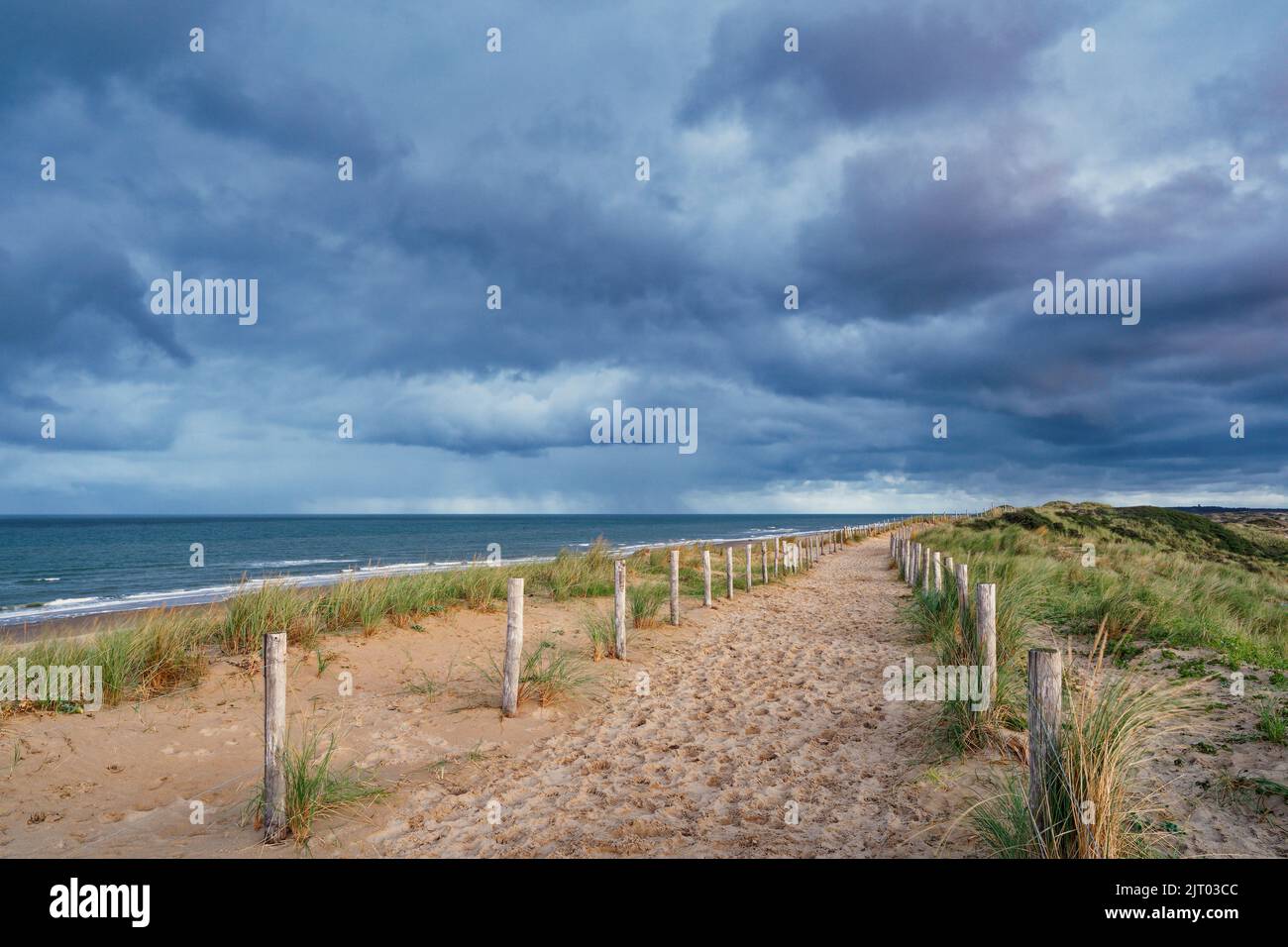 A beautiful sandy path along the ocean. Dramatic clouds in the sky ...