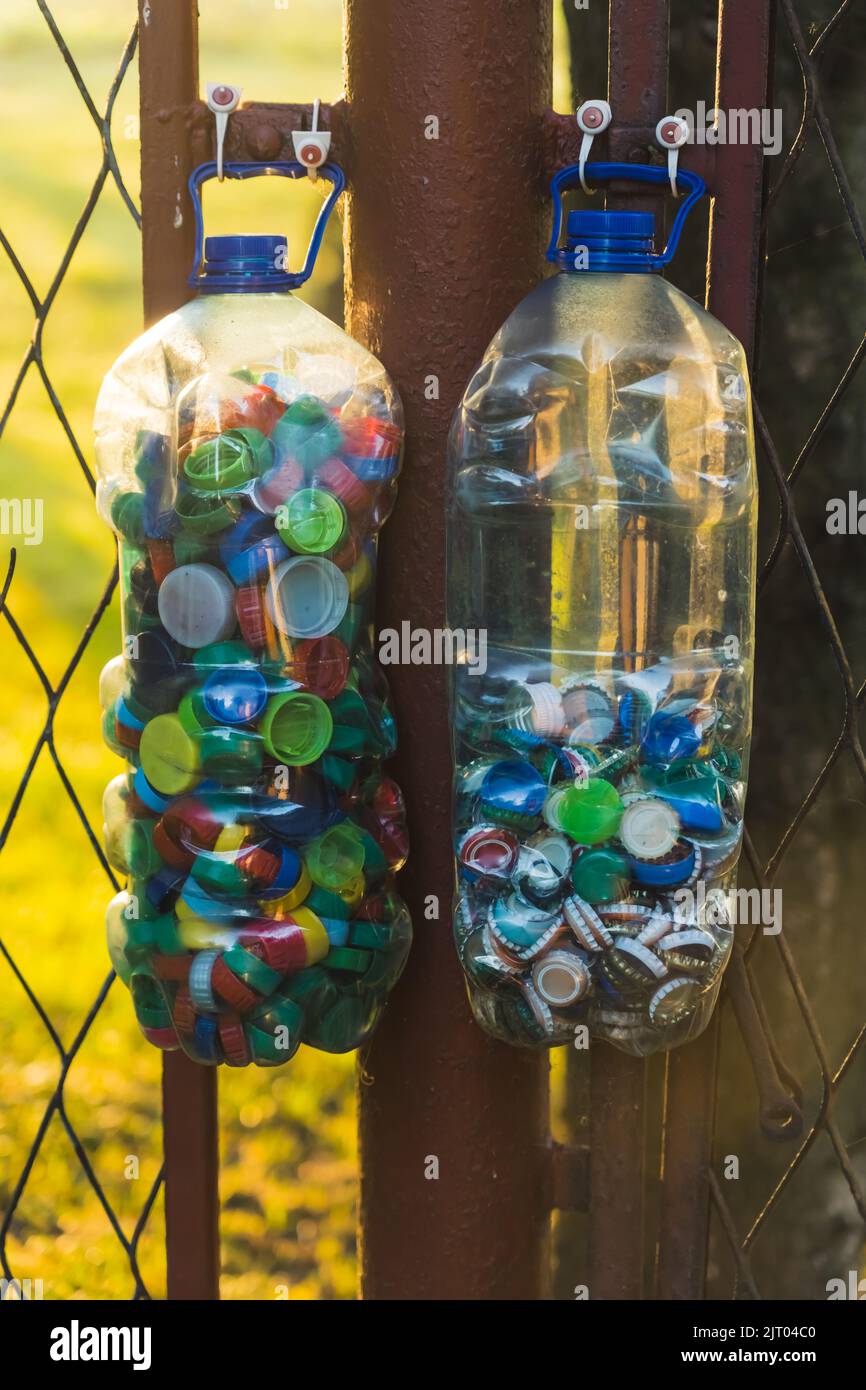 Plastic water jugs filled with plastic bottles hanging on metal fence ...