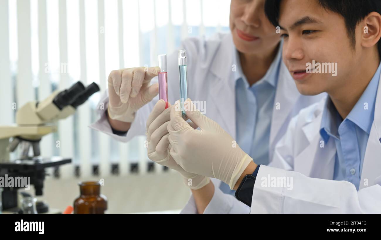 Senior woman supervisor and young man specialist analyzing liquid biochemicals, conducting ...