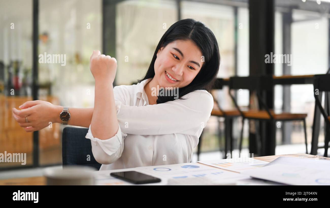 Happy asian female office worker relaxing at work and stretching her ...