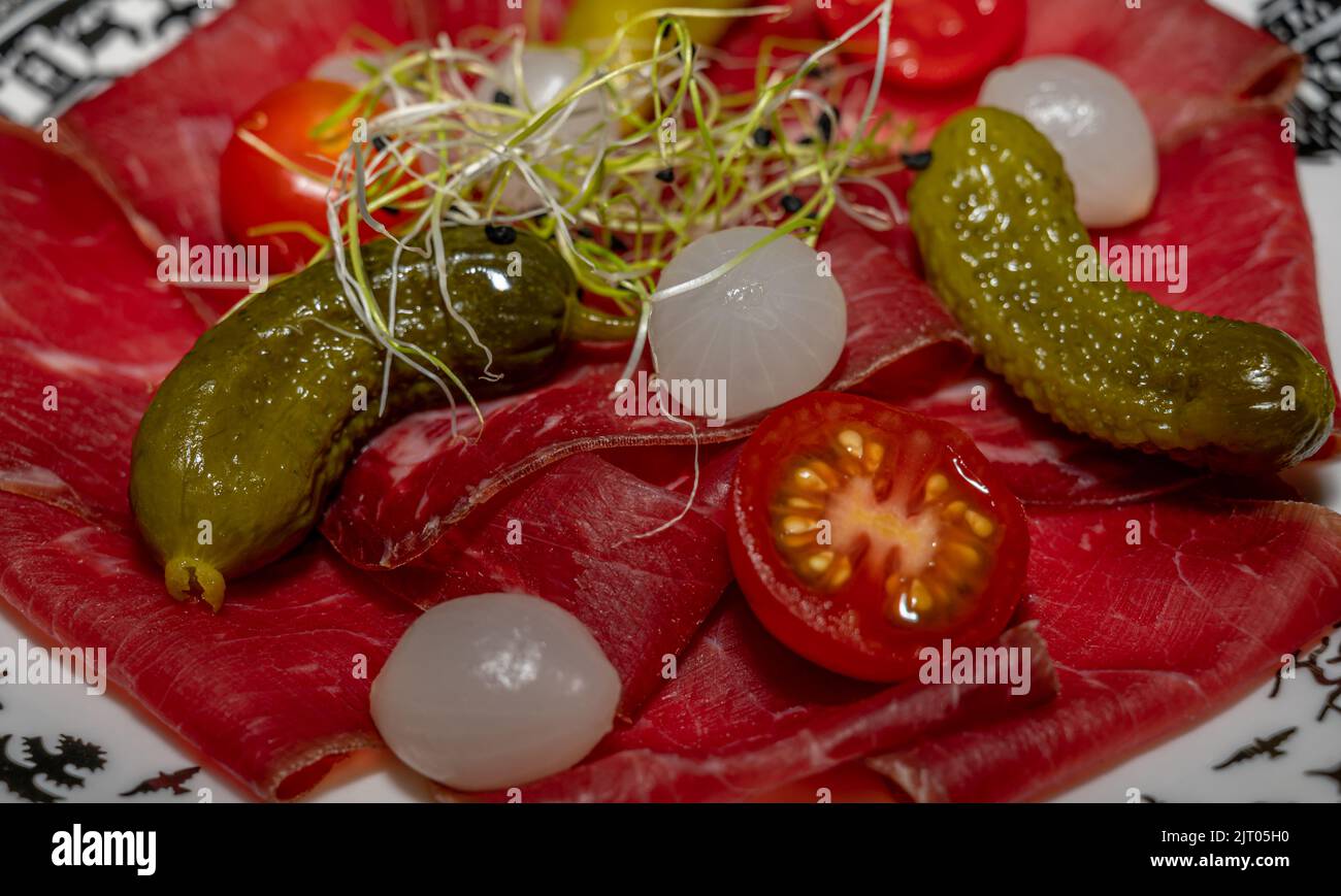 Sliced dried meat, pickled cucumber and onions. Food appetizer concept ...