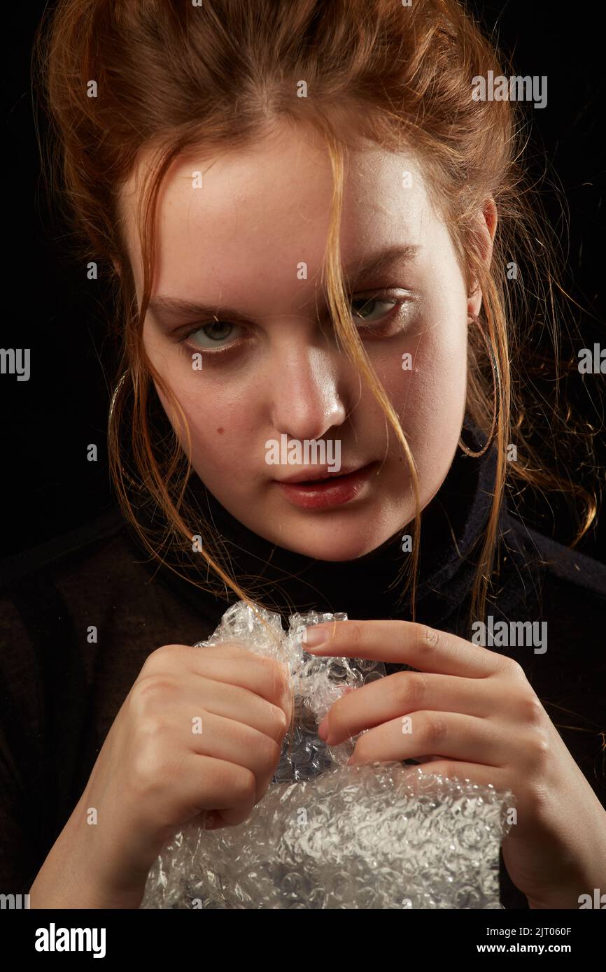 stressed woman in depression bursts bubbles of packaging cellophane ...