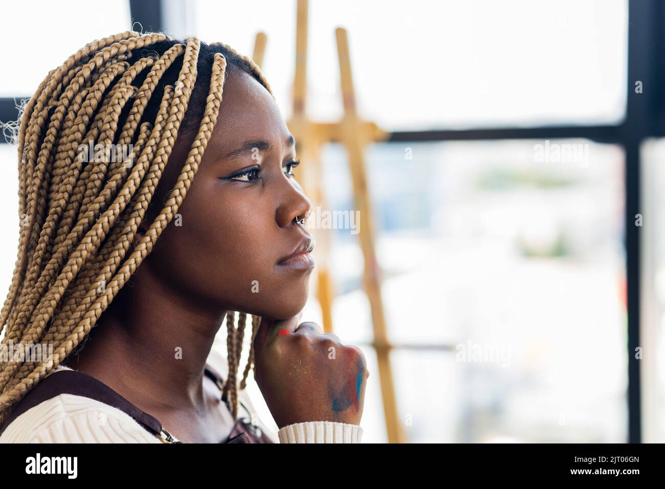 african american woman sitting next to blank white canvas on easel in ...