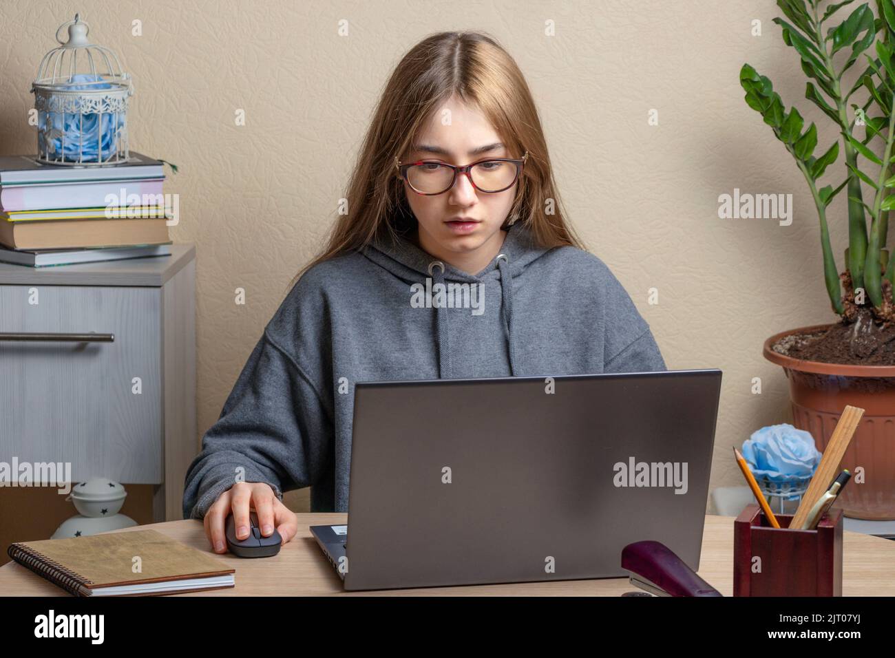 pretty young girl looks at the laptop screen in her room. online class ...